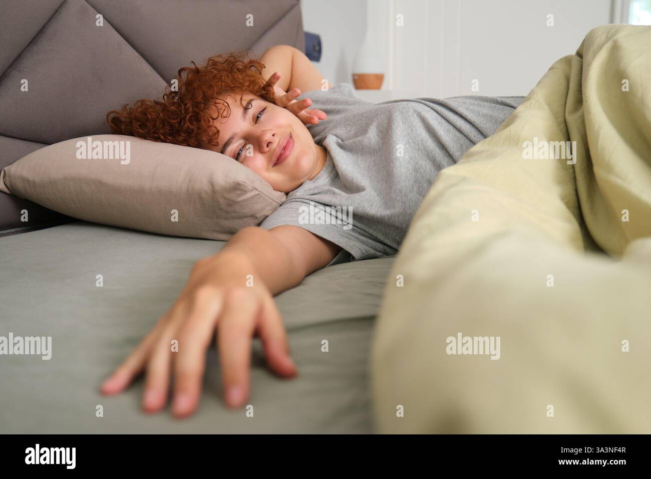 Young woman waking up and stretching in bed after good sleep Stock ...