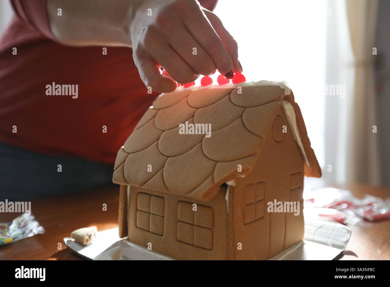 Hands decorating gingerbread house roof with candy Stock Photo - Alamy