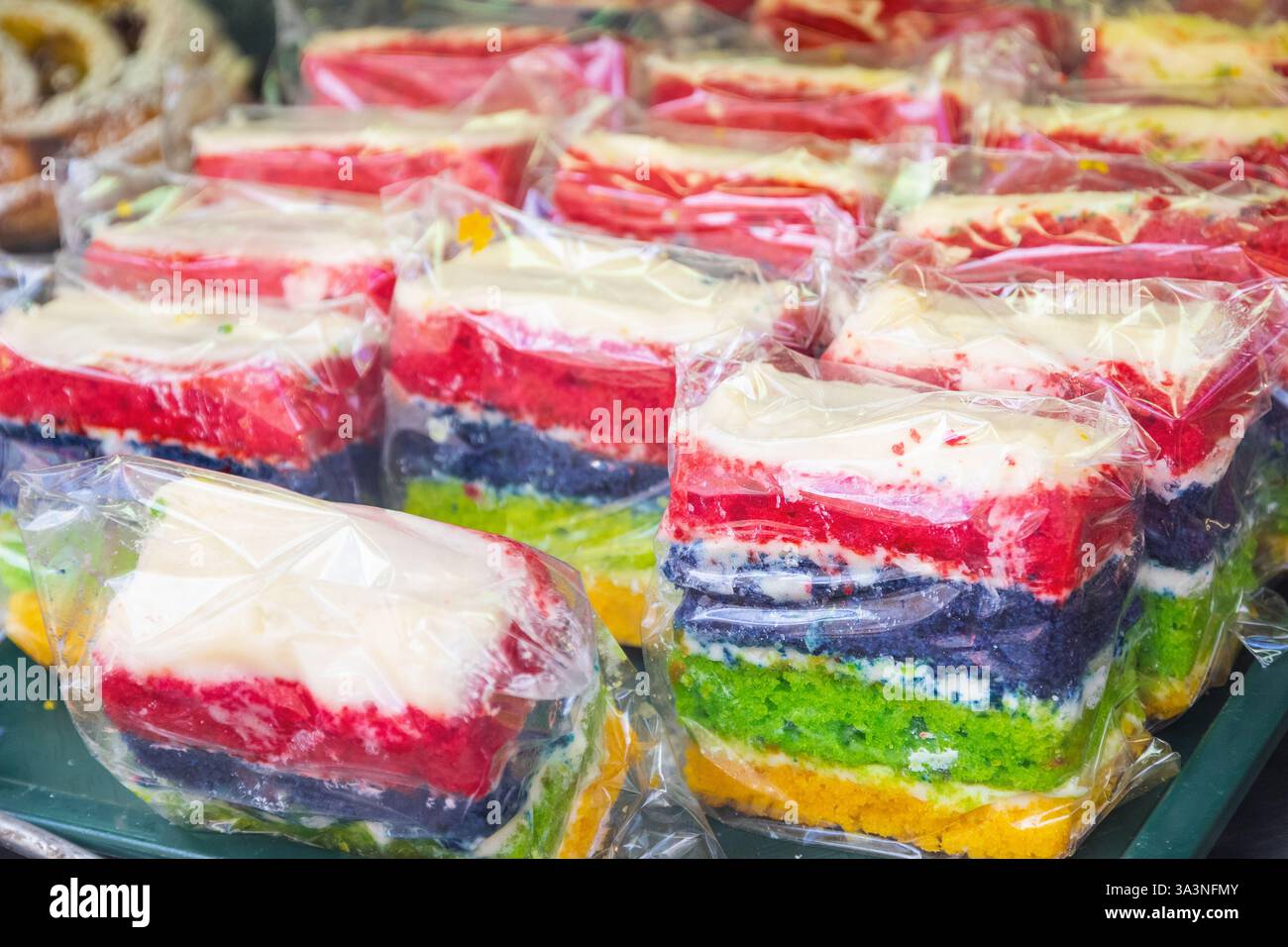 Slices of rainbow sponge cakes displayed at Brick Lane market in London ...