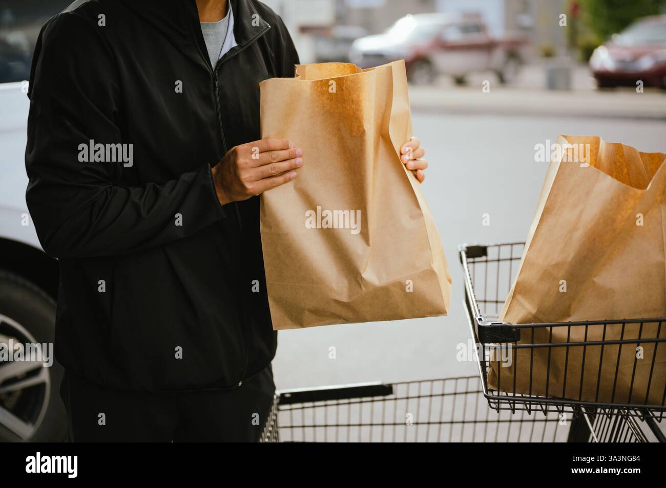 Person lifting paper grocery bag from a shopping cart outdoors Stock ...