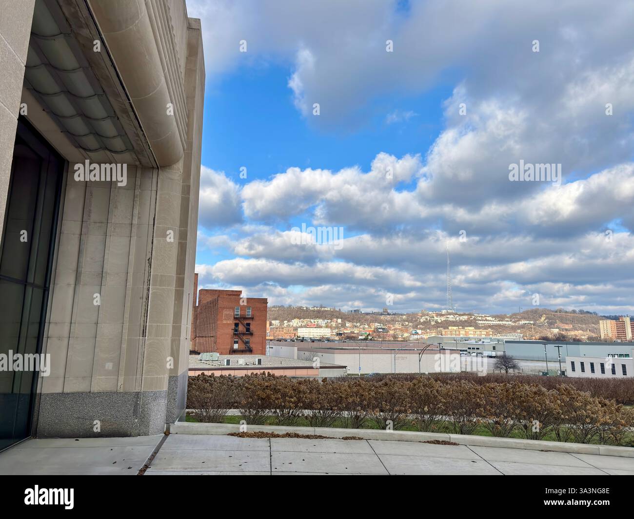 Modern stone building corner with urban skyline and cloudy blue sky ...