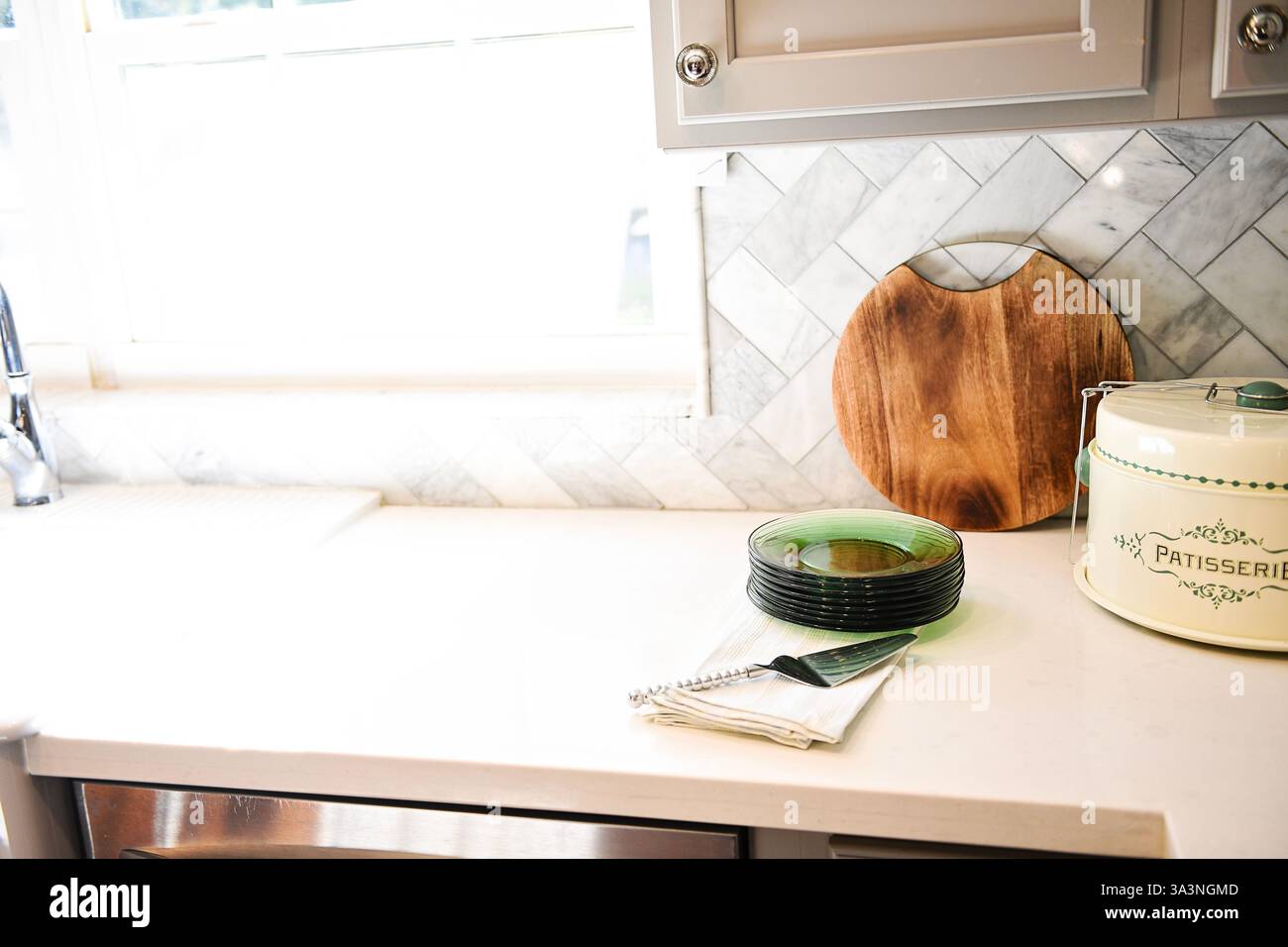 Bright kitchen counter with green plates, a wooden board, and pa Stock ...