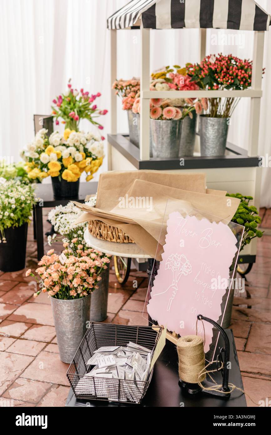 Flower bar setup with blooms, wrapping paper, and pink sign Stock Photo ...