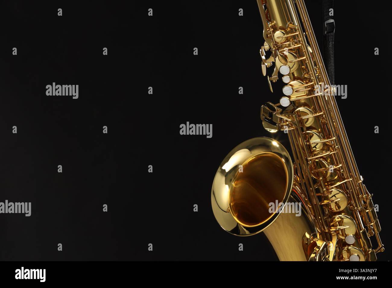 Jazz. One beautiful saxophone hanging from strap on black background ...