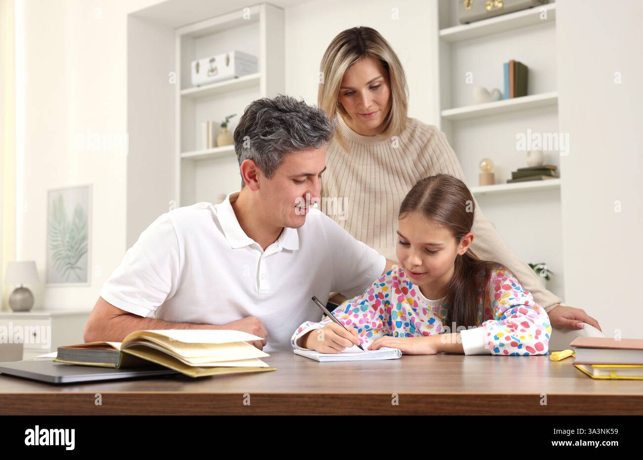 Parents helping their daughter with homework at table indoors Stock Photo - Alamy
