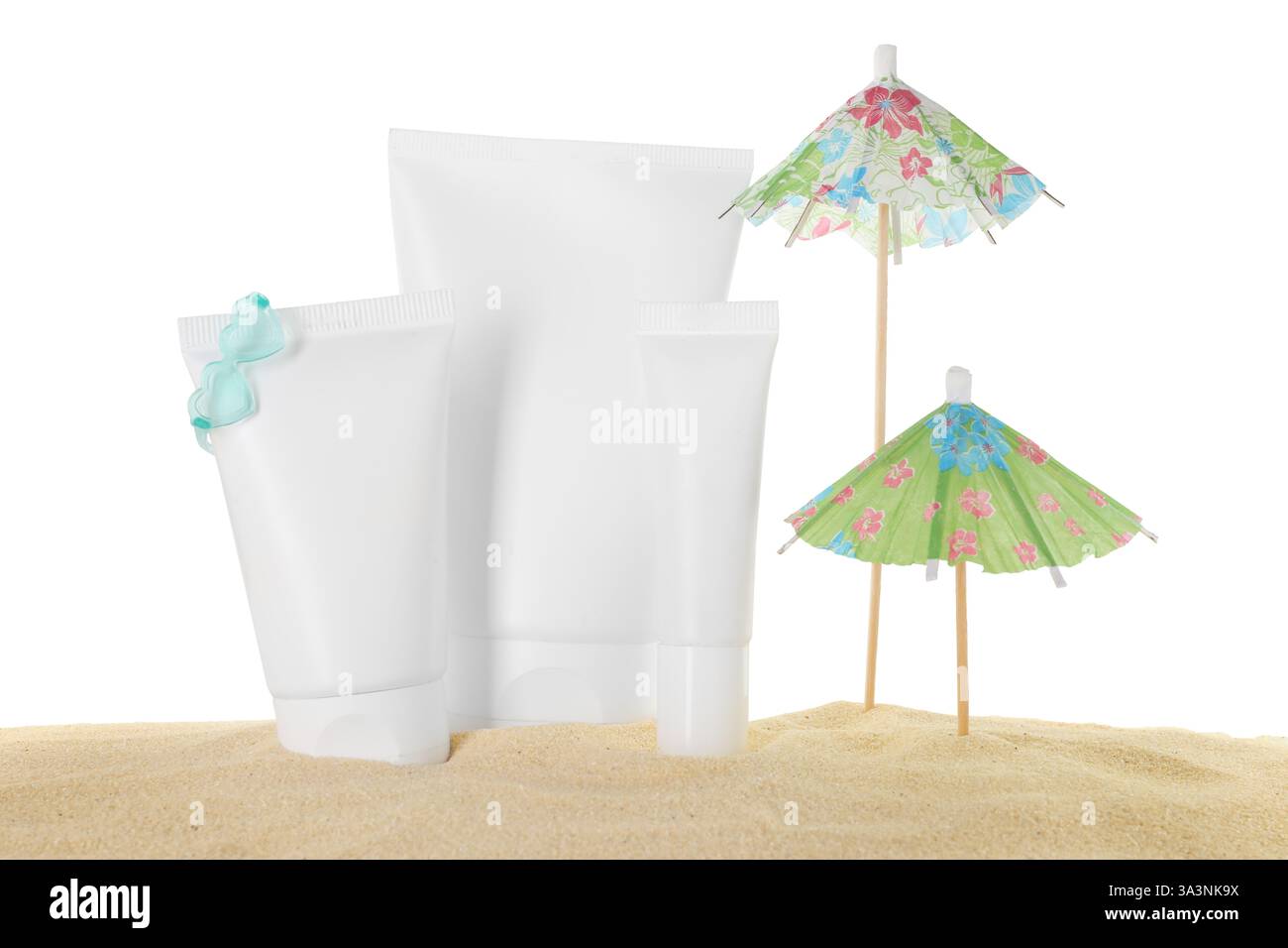 Tubes of sun protection product and small umbrellas on sand against ...