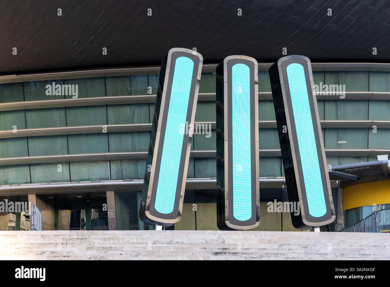 Three towering light columns with cyan blue screens stand in front of ...