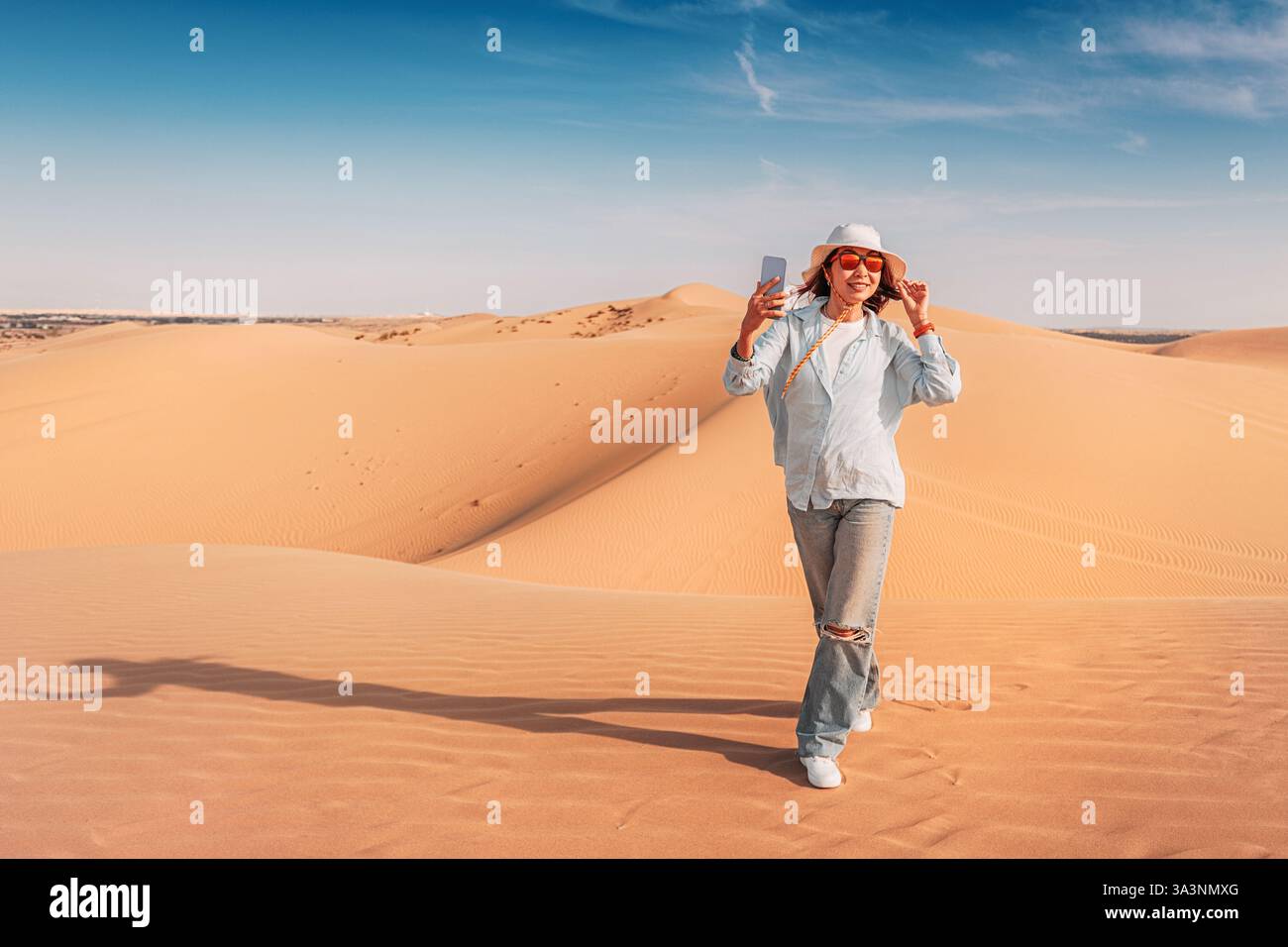 Smiling tourist taking pictures in desert using mobile phone, enjoying ...