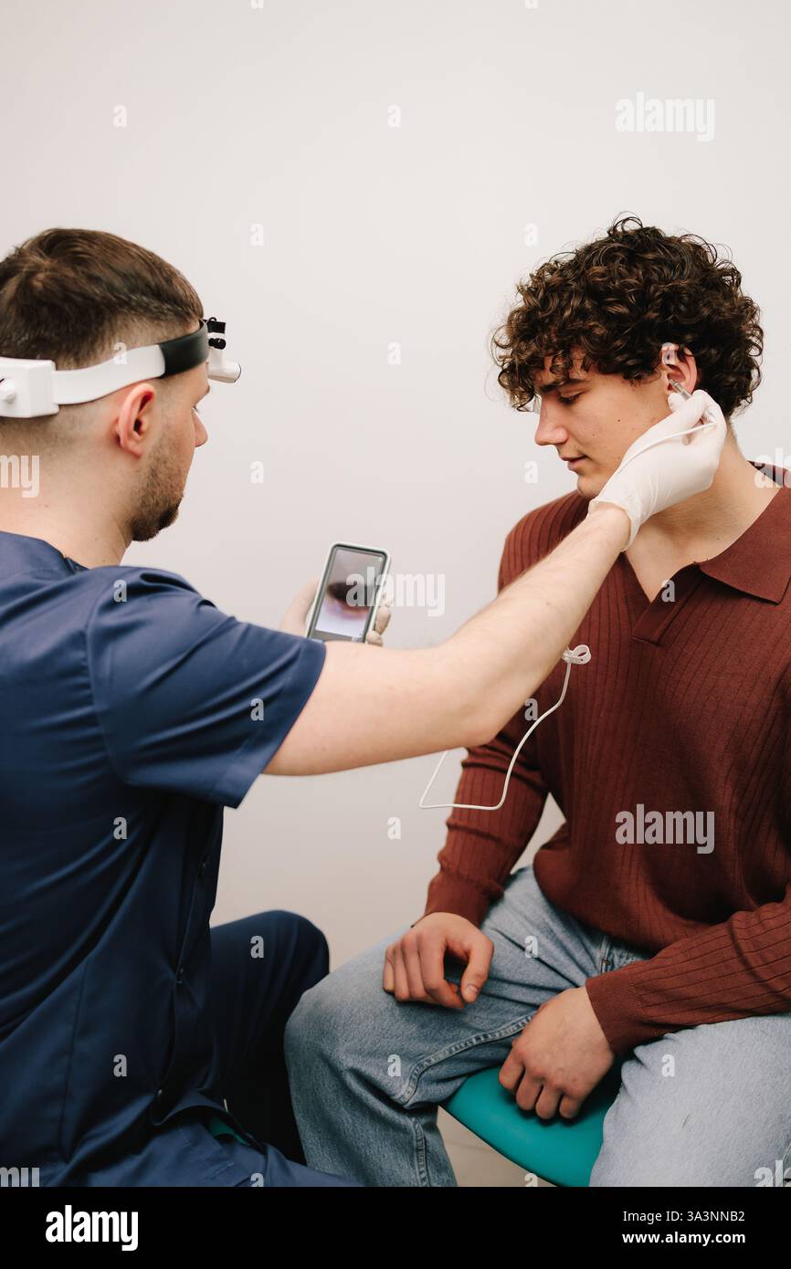 Man patient and ENT doctor look at the screen of a digital otoscope ...