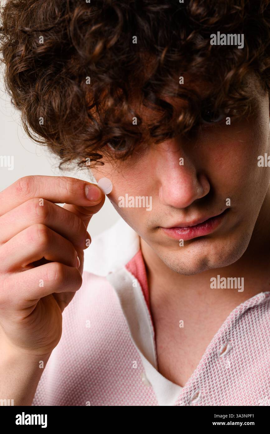 Using acne pimple patch to clean the face from zits. Young man uses ...