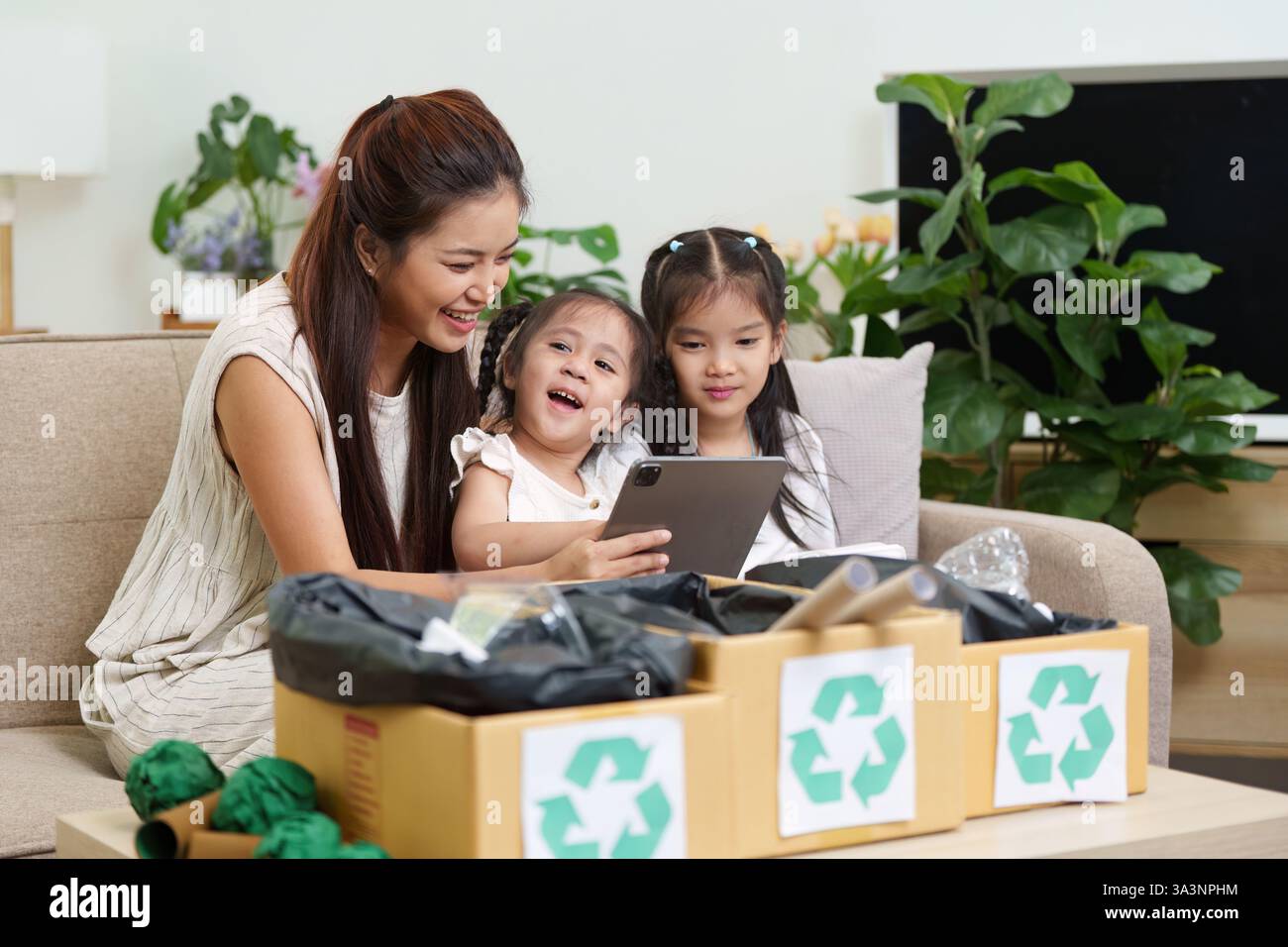 Family Bonding and Recycling Fun. A mother and her kids enjoying a recycling project, fostering ...