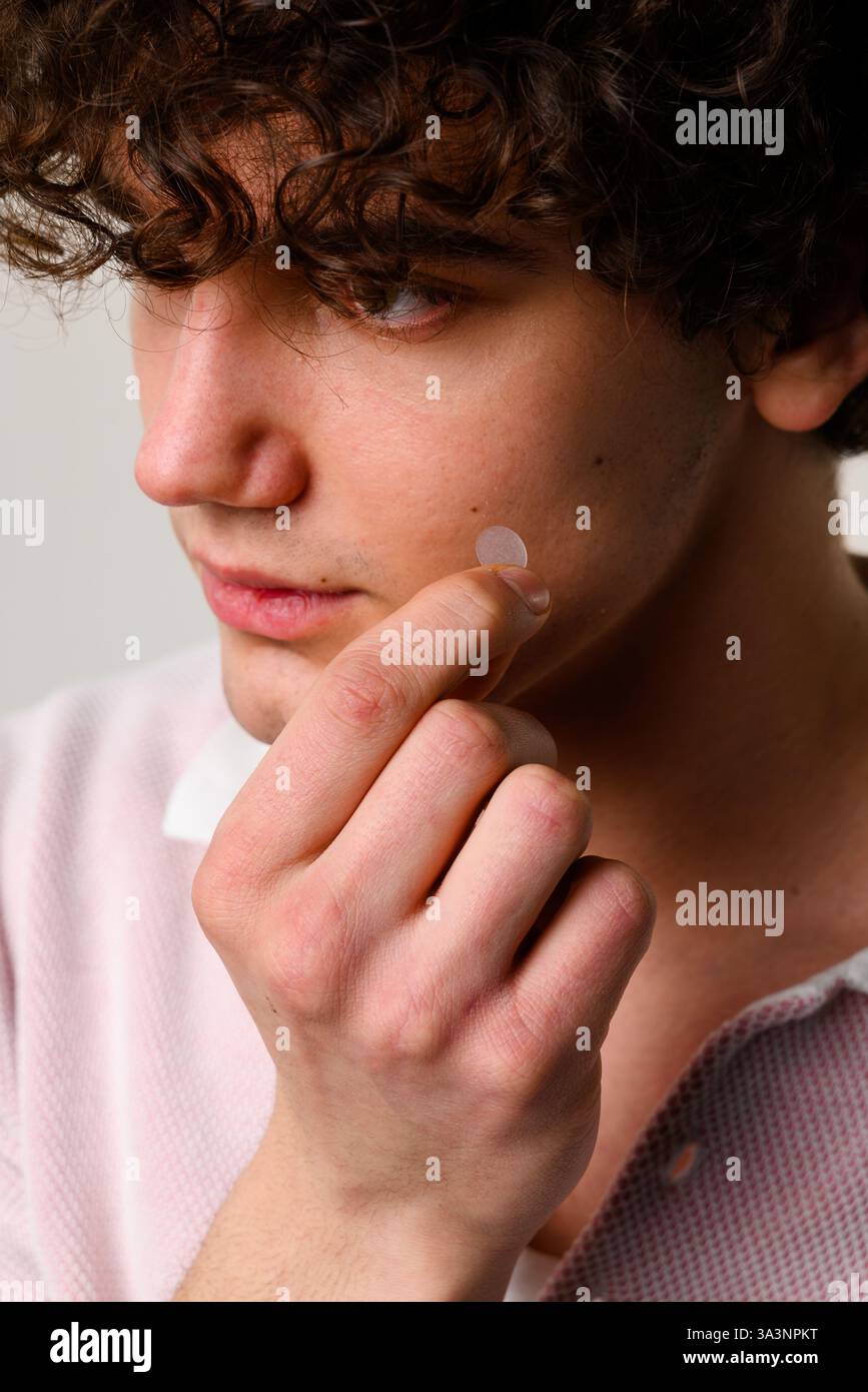 Using acne pimple patch to clean the face from zits. Young man uses ...
