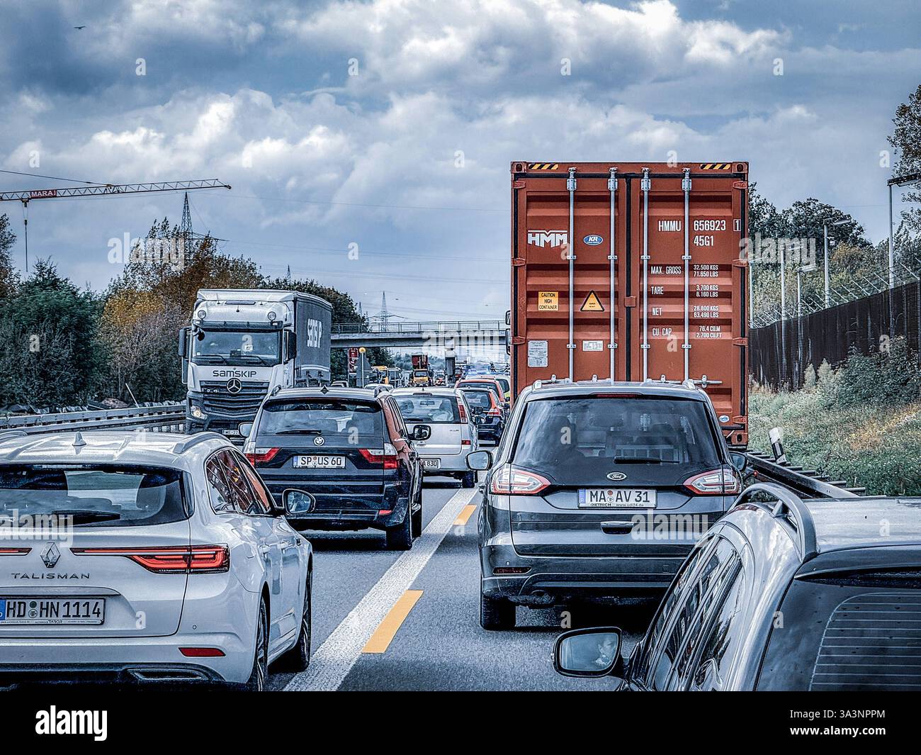 Stau auf Autobahn, Lkw, Autos, Brücke, Baukran, bewölkter Himmel ...