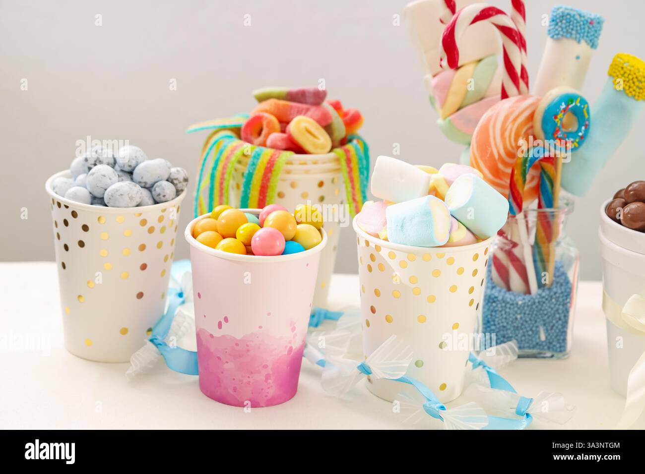 Candy bar. Different yummy sweets on white table against grey ...