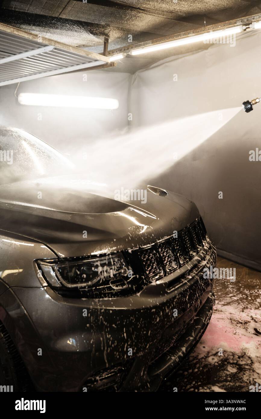 Washing the foam from the surface of the vehicle. Cleaning the car body ...