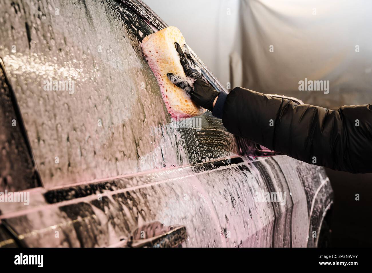 Cleaning the vehicle side window using a sponge and pink foam detergent ...