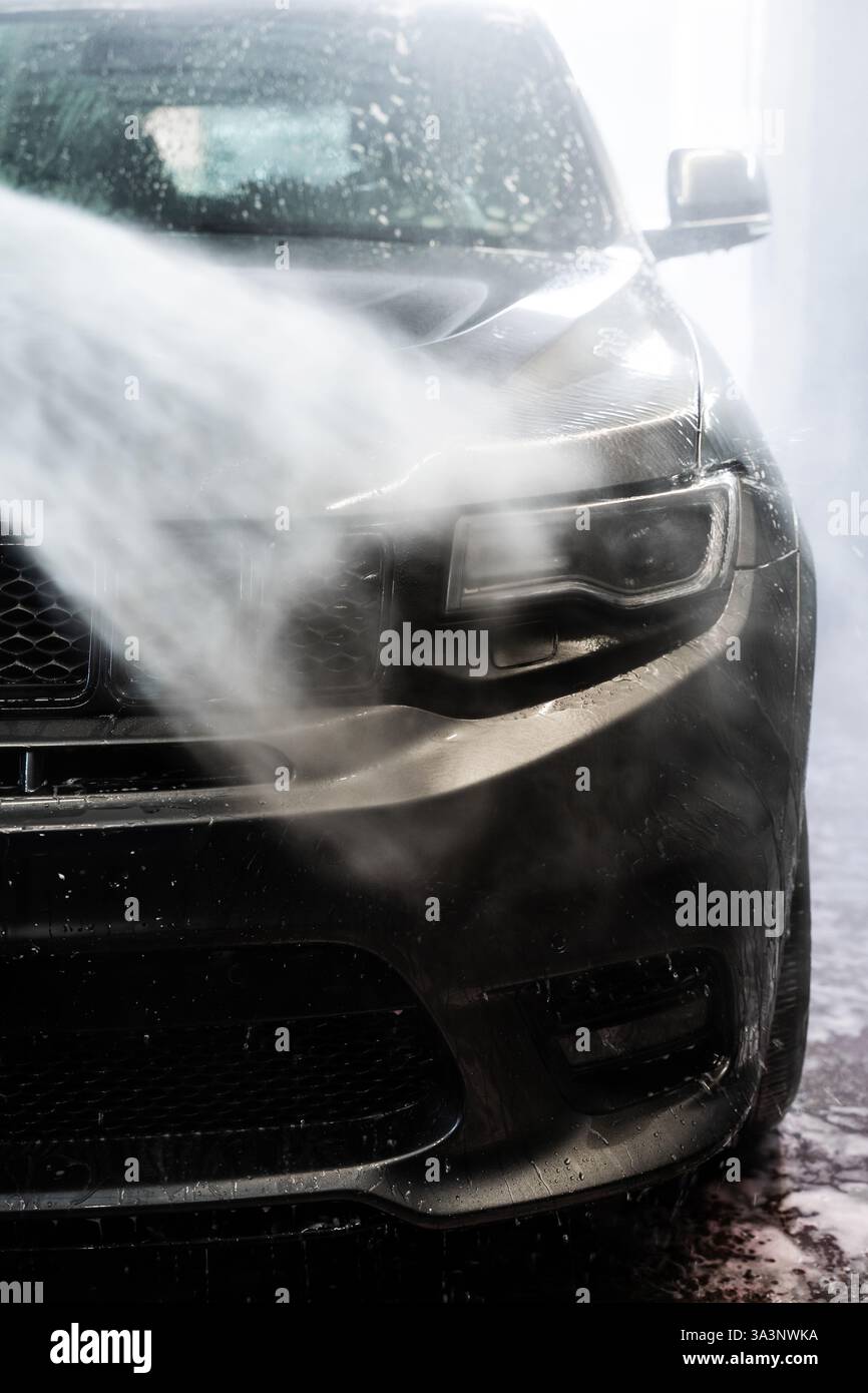 Using high pressure water jet to clean dirt from car body. Cleaning off ...