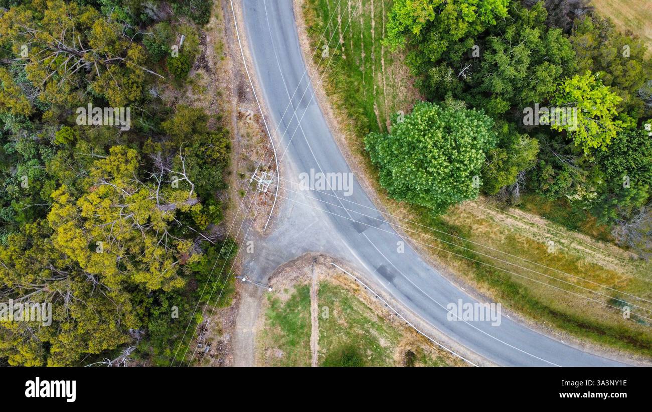 A winding road with a power line running above it, seen from above ...
