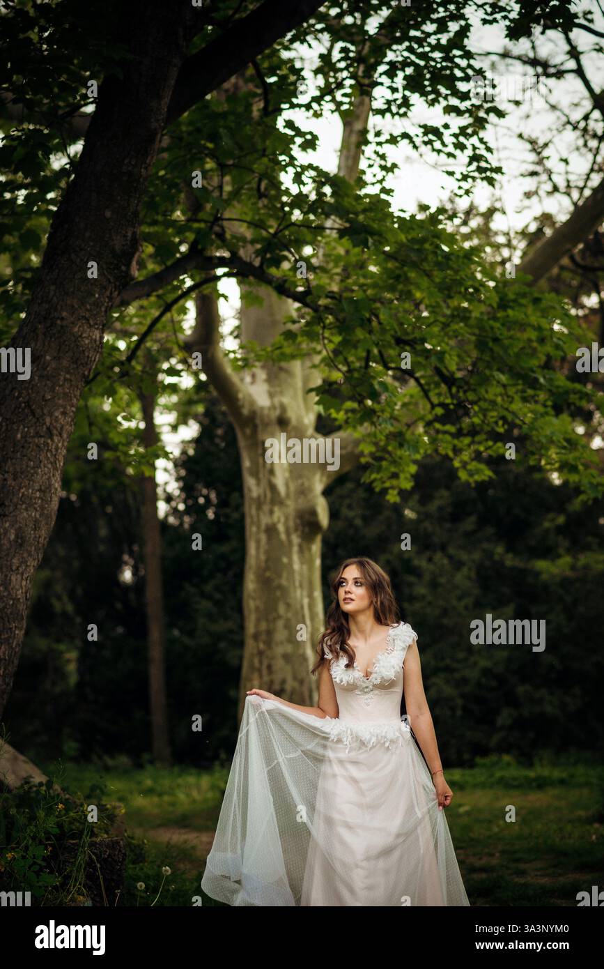 Stunning bride gracefully poses in a spring park, among blossoming ...