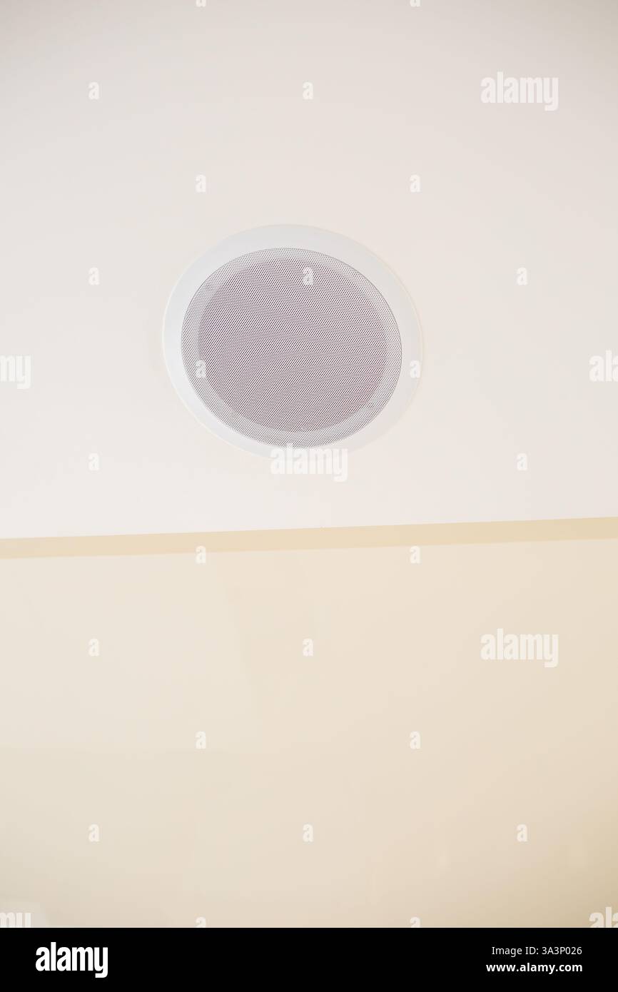 A white circular air vent is prominently hanging from the ceiling of ...