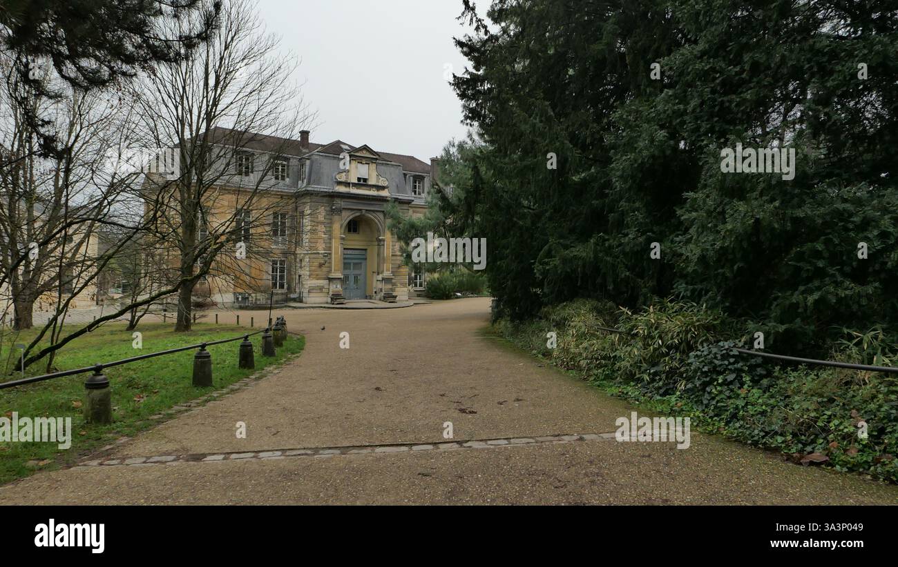 A large, vintage mansion stands at the end of a tree-lined gravel path ...