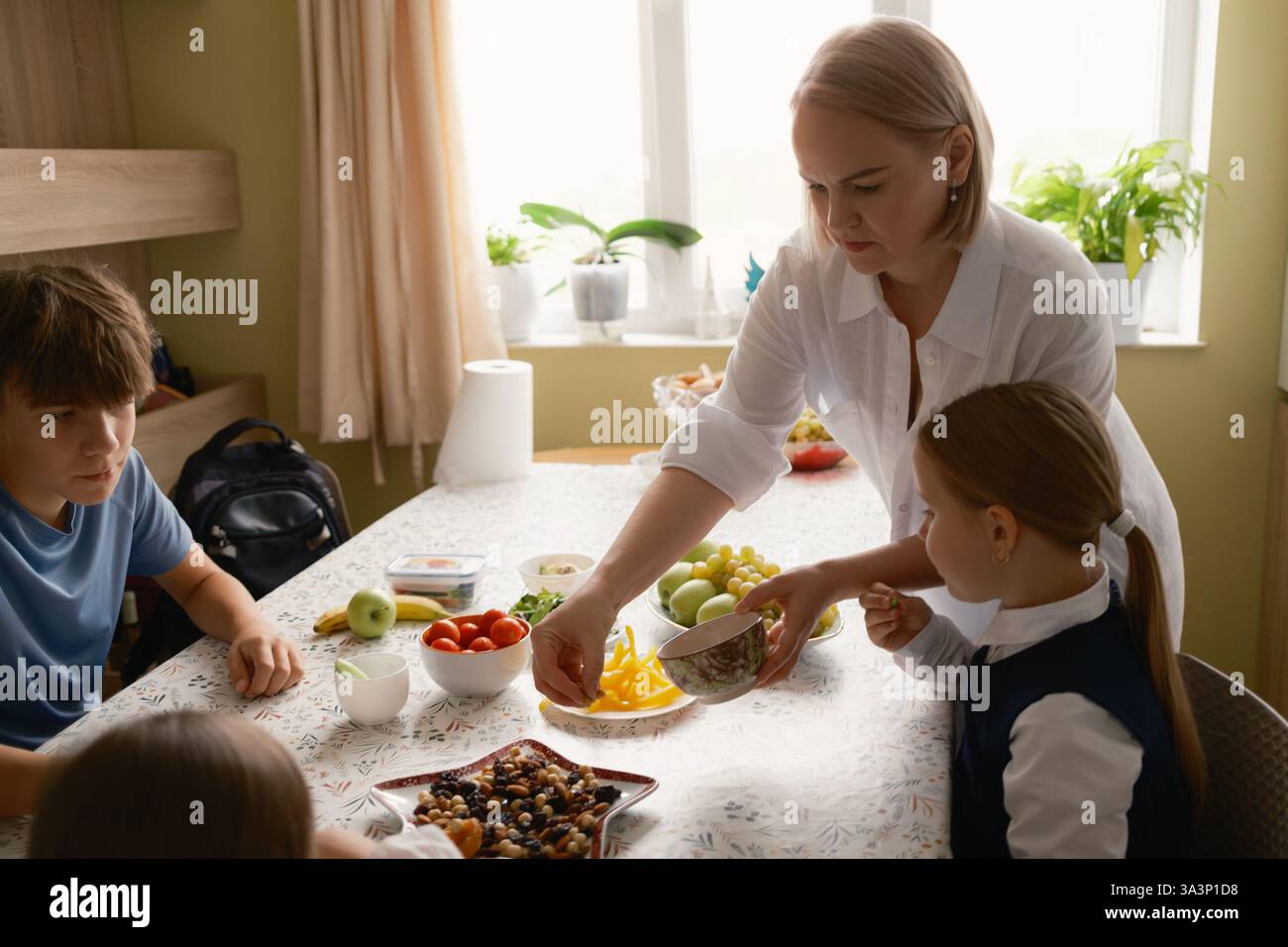 Mother helping children prepare breakfast before school day Stock Photo ...