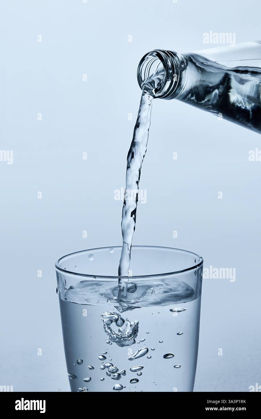 Close-up photo of water being poured from glass bottle into clear glass ...