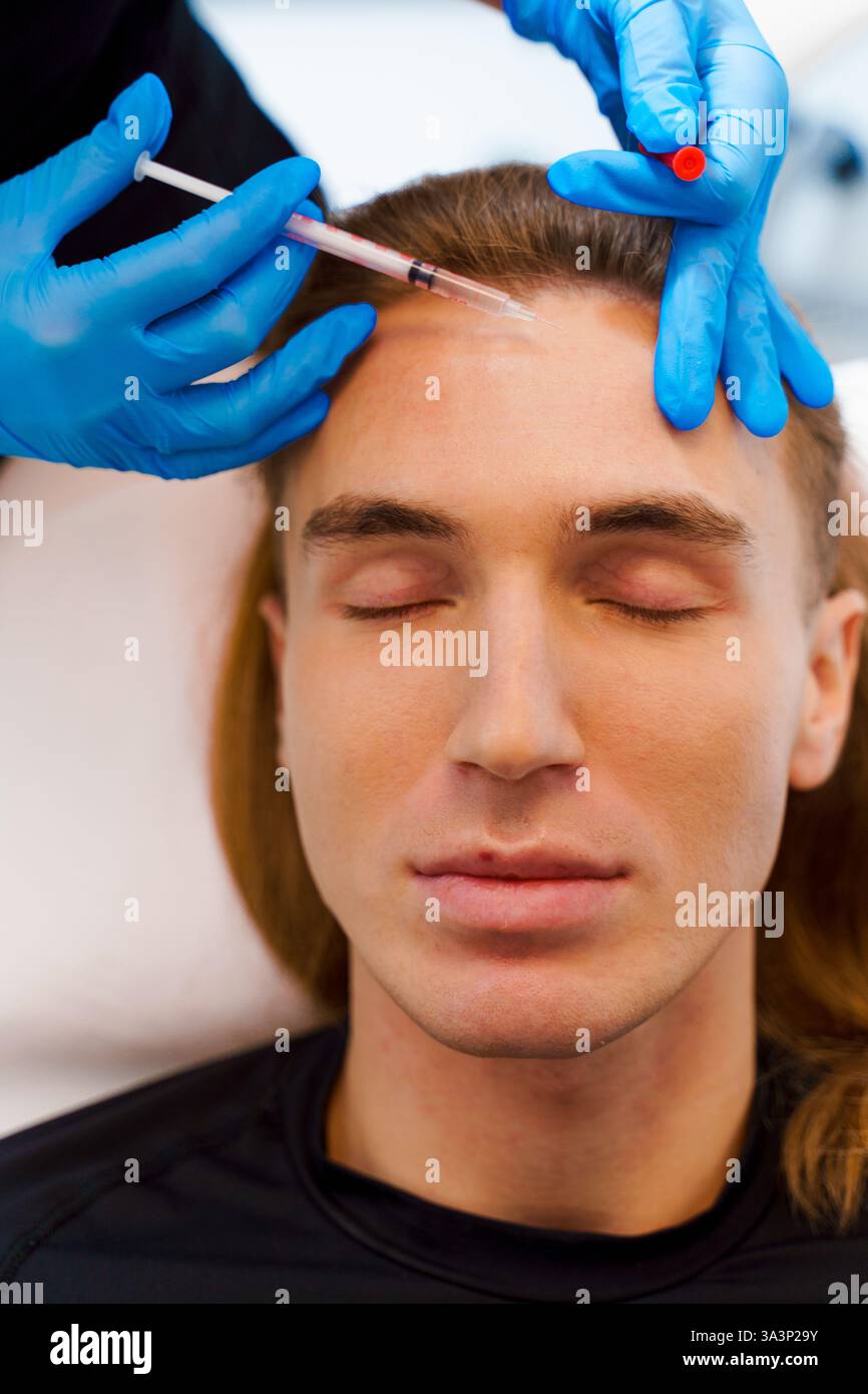 Botulinum toxin injection procedure on the man's forehead in the beauty ...