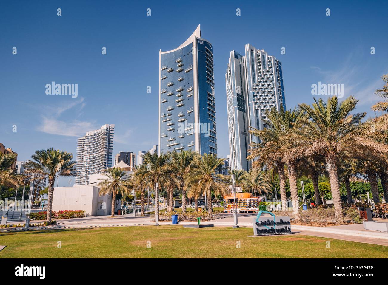 21 January 2025, Abu Dhabi, UAE: Lush palm trees and a paved promenade ...