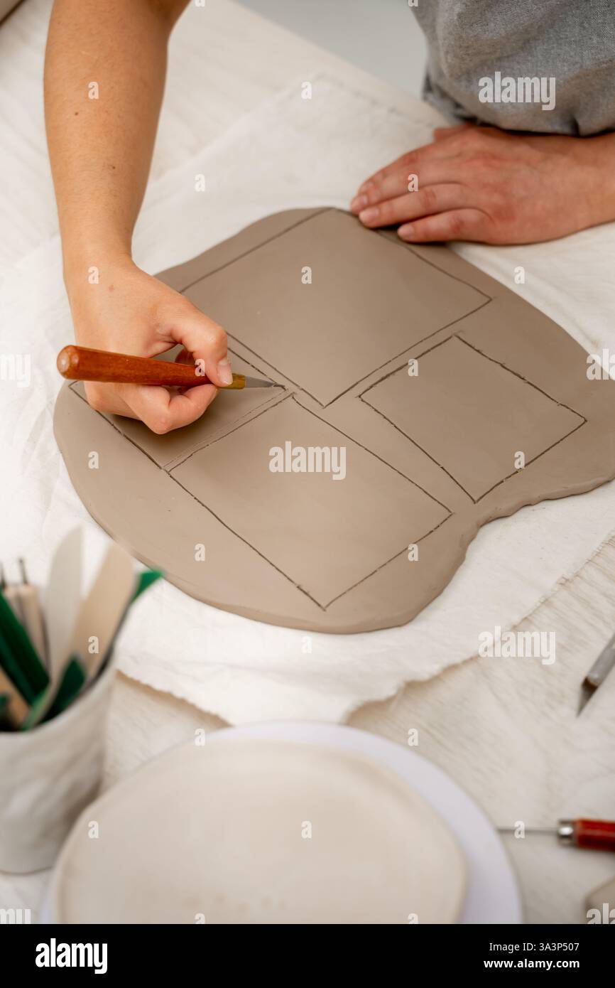 Cutting out figures from a flat sheet of clay with a sculpting tool ...