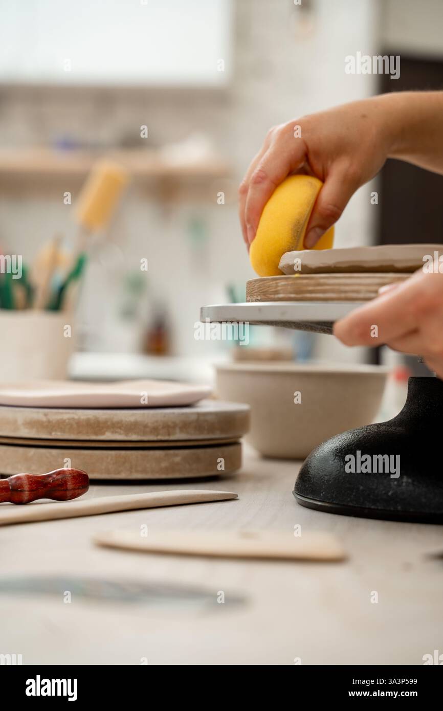 Ceramics workshop. Applying more moisture on clay products. Smoothing ...
