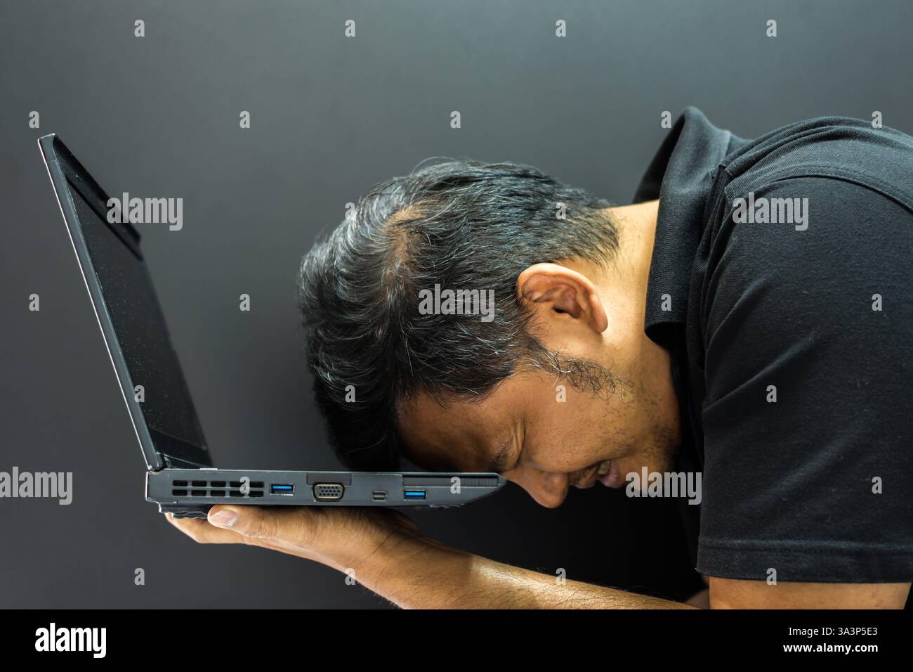 Asian man 40s in black polo shirt holding computer notebook or laptop ...