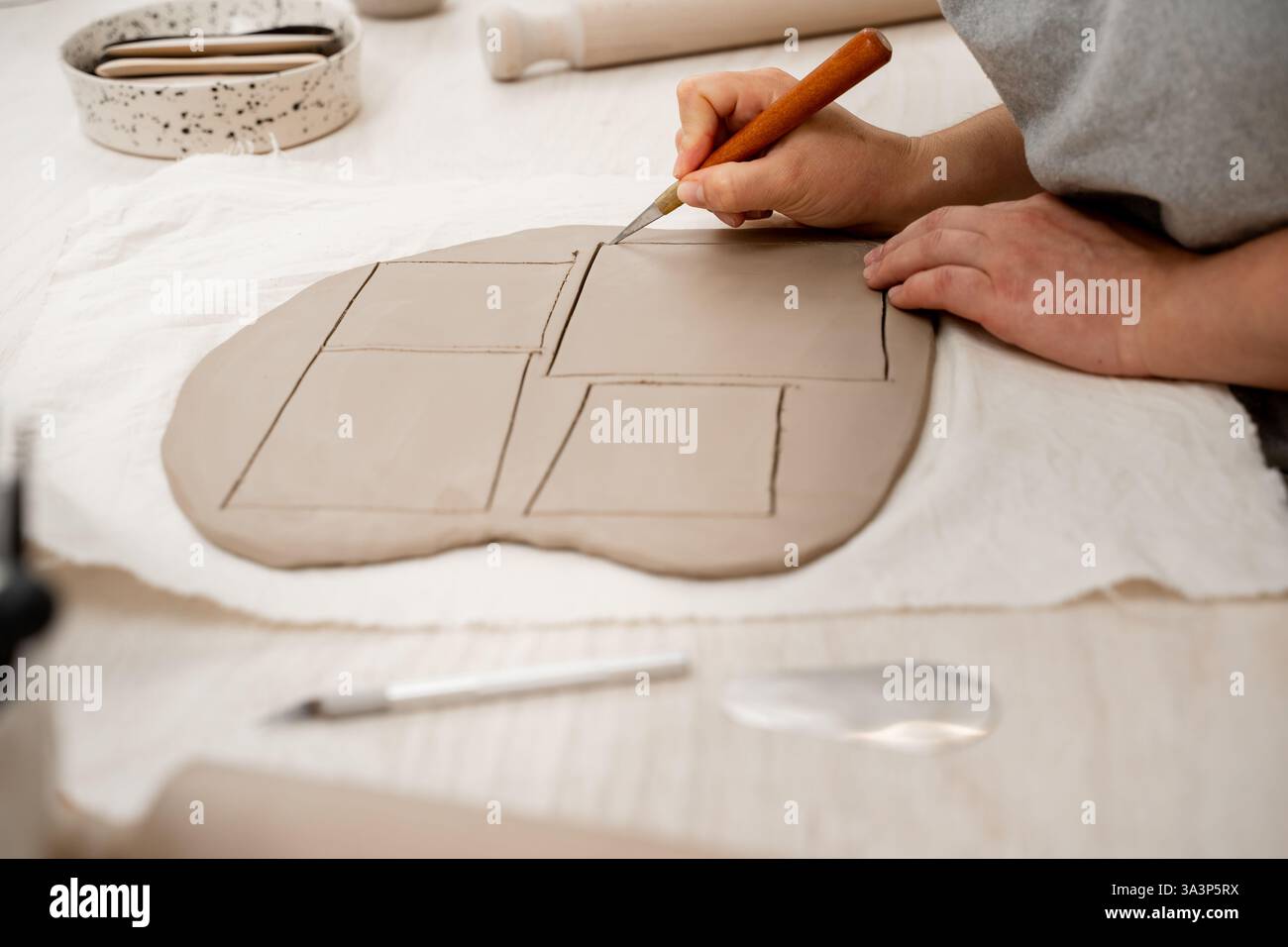 Cutting out figures from a flat sheet of clay with a sculpting tool ...