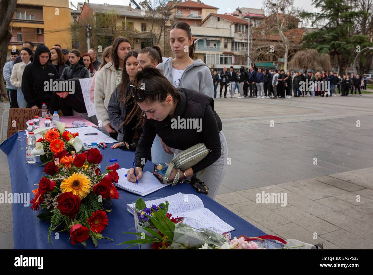 A woman writes a condolence message for the victims of a massive ...