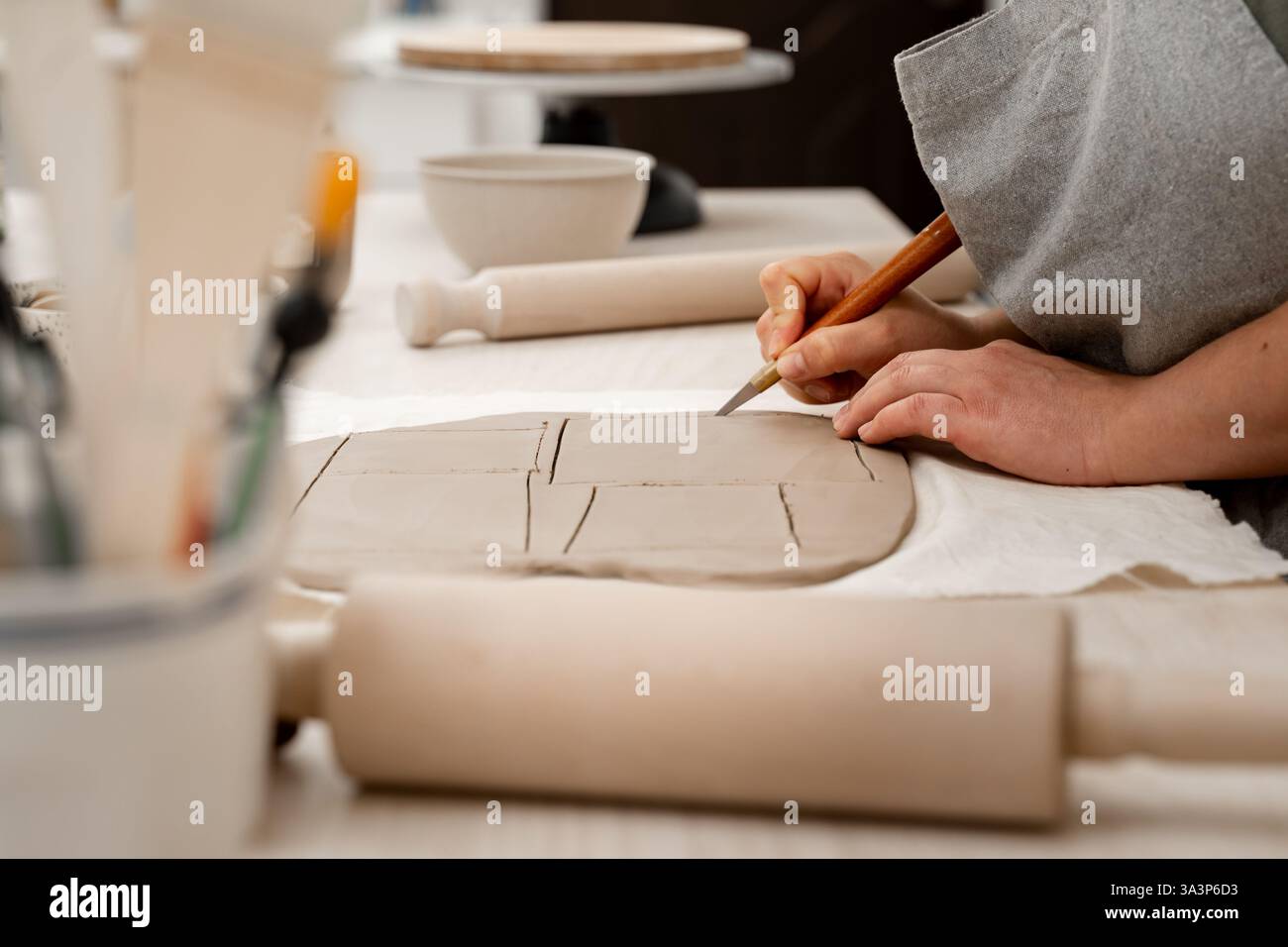 Girl is using a sharp clay cutter to cut off a shape from the piece of ...
