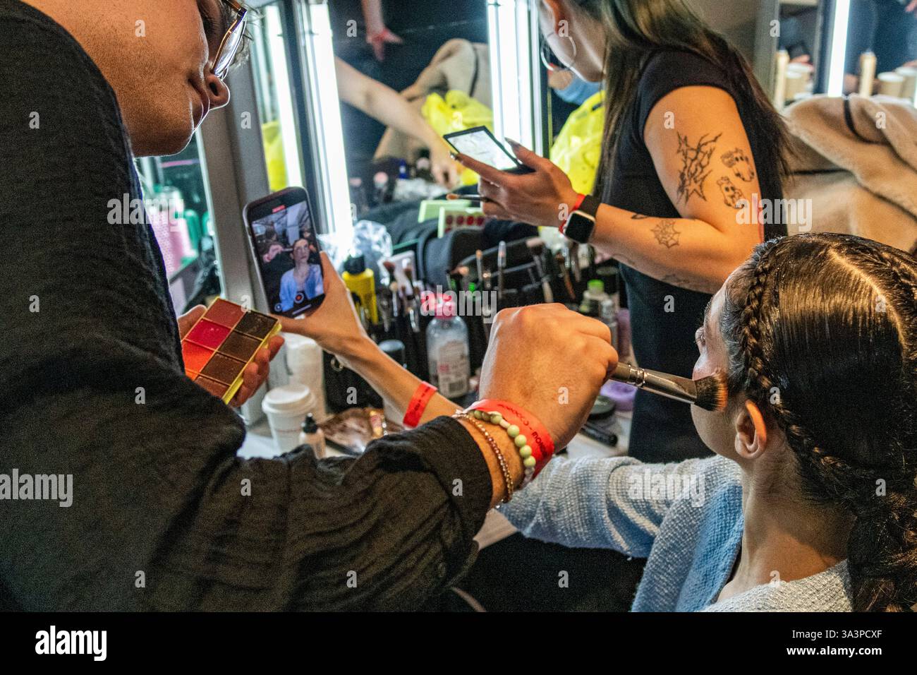 A female model having makeup applied to her by a makeup artist ...
