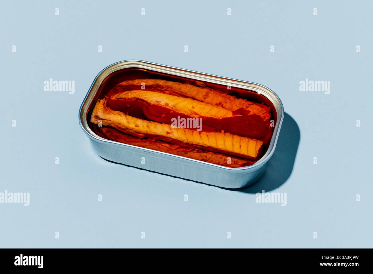 an open can of canned frigate tuna fillets placed on a light blue ...