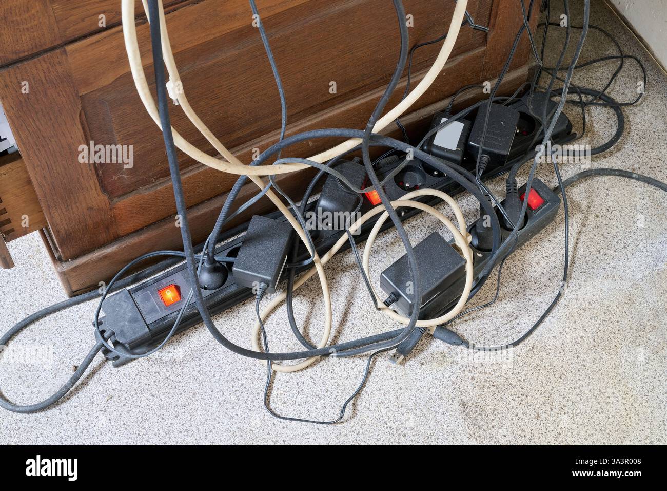 Lot of messy cables on the floor near wooden desk Stock Photo - Alamy