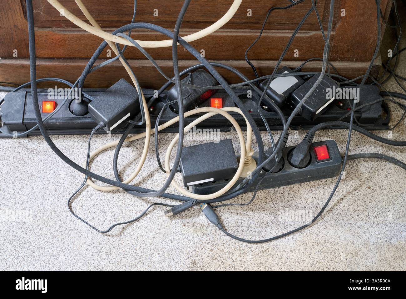 Lot of messy cables on the floor near wooden desk Stock Photo - Alamy
