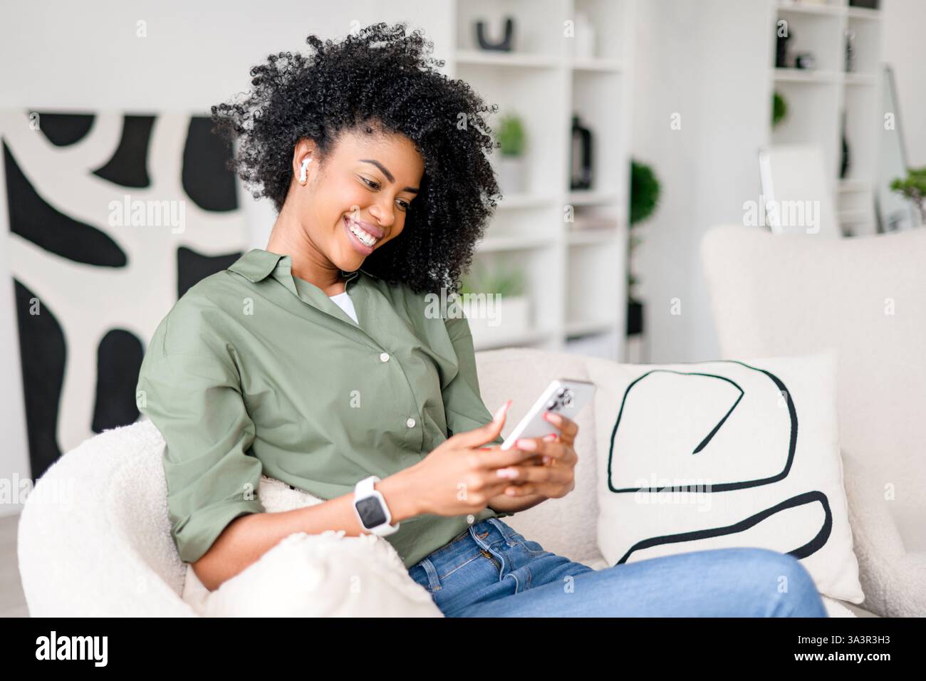 A cheerful African-American woman comfortably lounges on a couch while ...