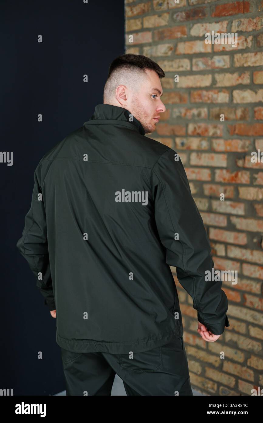 A man wearing a sleek black jacket is confidently standing in front of ...