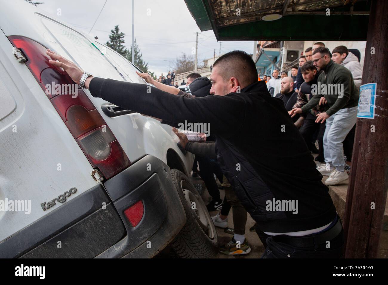 People push a car on its side while protesting near the home of the ...
