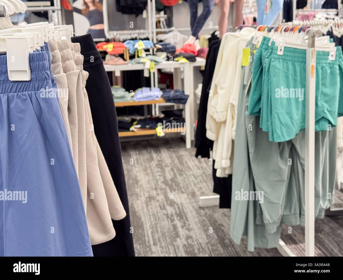 a retail store's clothing section with neatly hung shorts and pants in ...