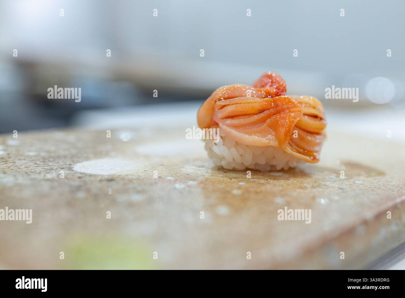 Single piece of blood cockle nigiri sushi placed on a textured stone ...