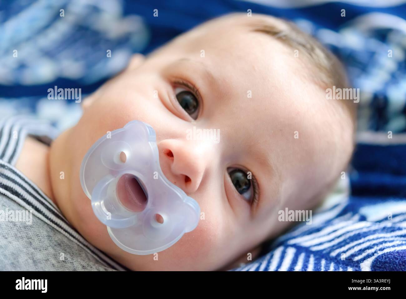 Cute boy laying down on bed and looking at camera Stock Photo - Alamy