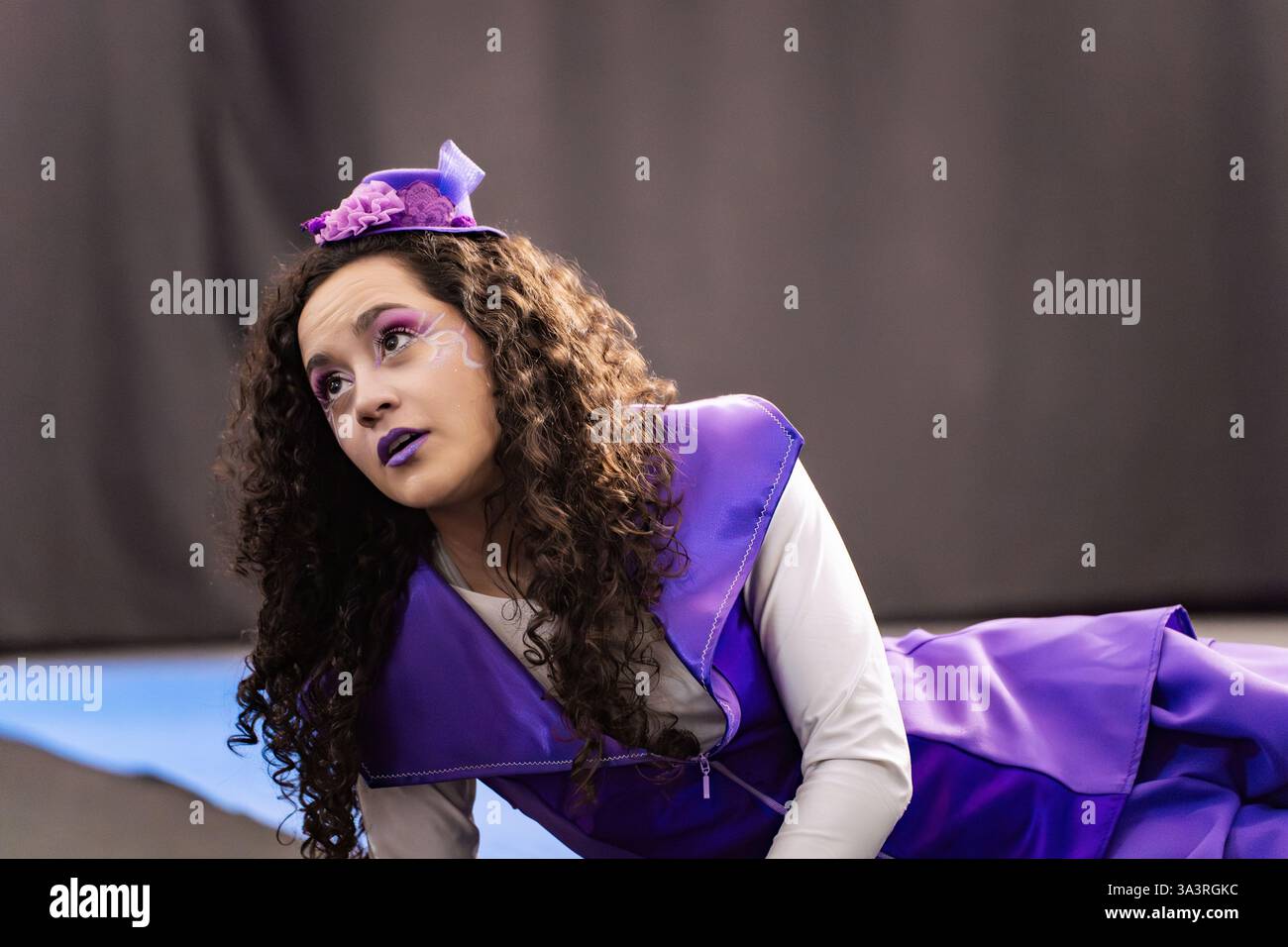Young actress with purple makeup and costume rehearsing a theatrical ...