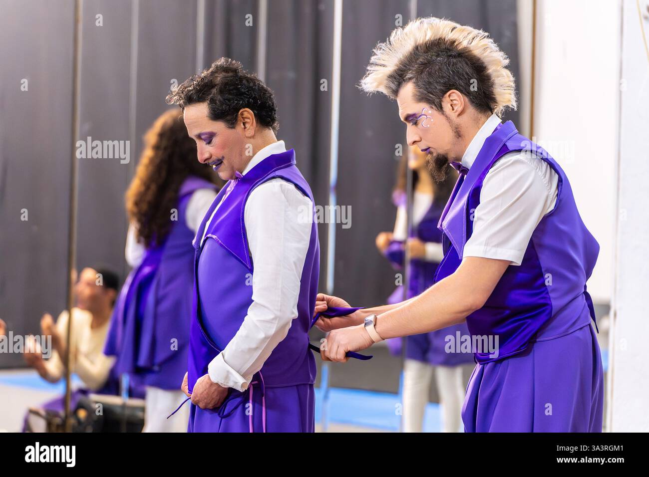 One stagehand tying the costume of another stagehand, getting ready for ...