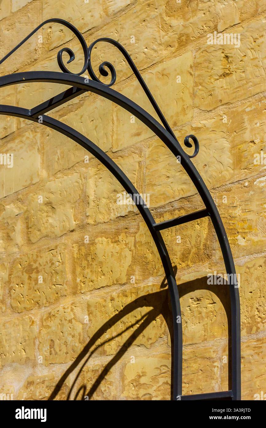 Ornate Metal Archway Against Weathered Stone Wall in Bright Sunlight ...