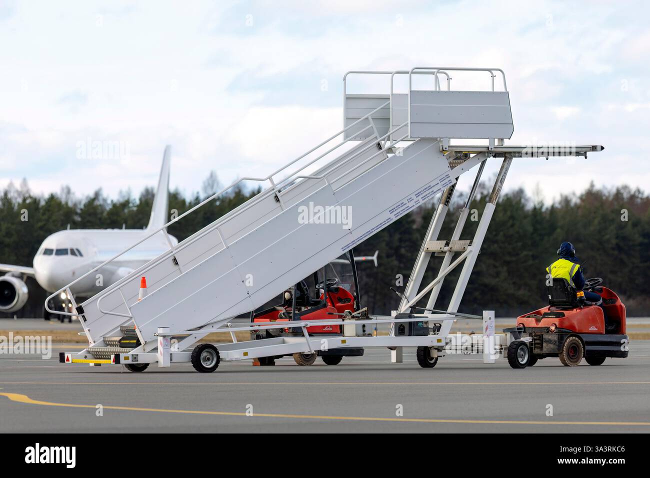 A mobile passenger boarding stair is positioned on an airport tarmac ...