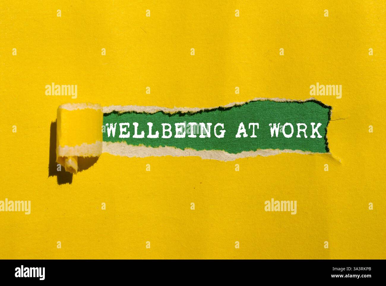 Wellbeing at work message written on ripped torn yellow paper on green ...